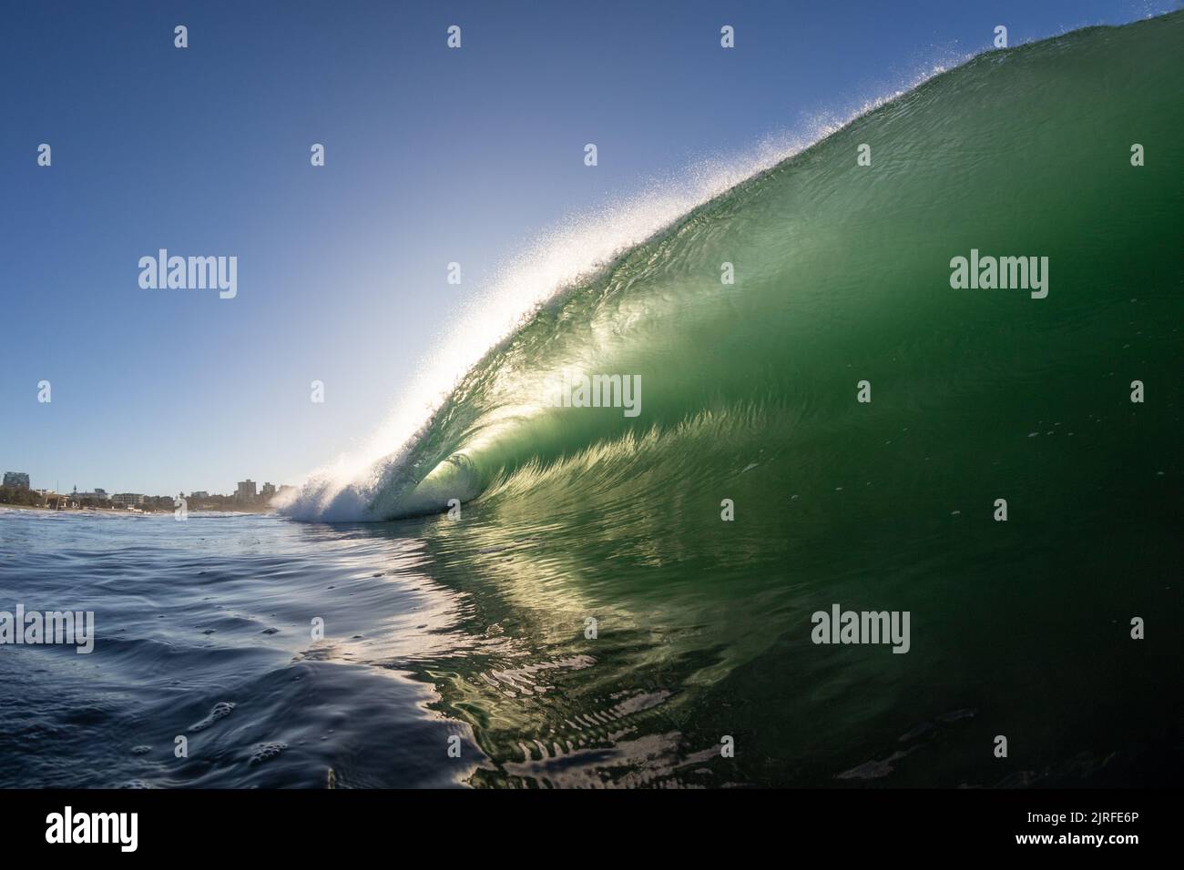 A closeup of a high clean wave on the sea with sunshine behind Stock ...
