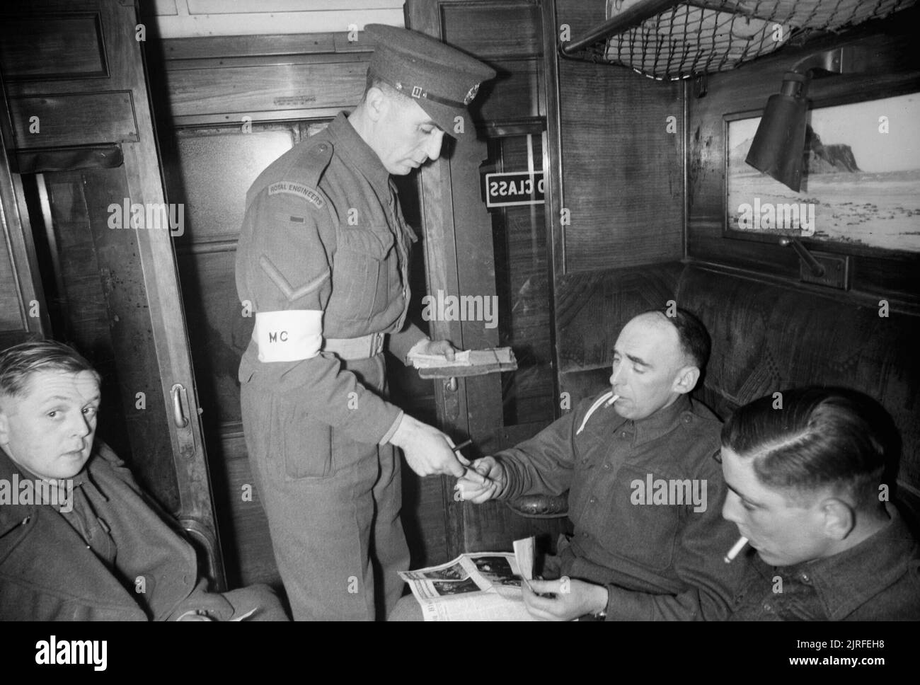A Lance Corporal of the Royal Engineers checks the tickets and passes of passengers in a ...