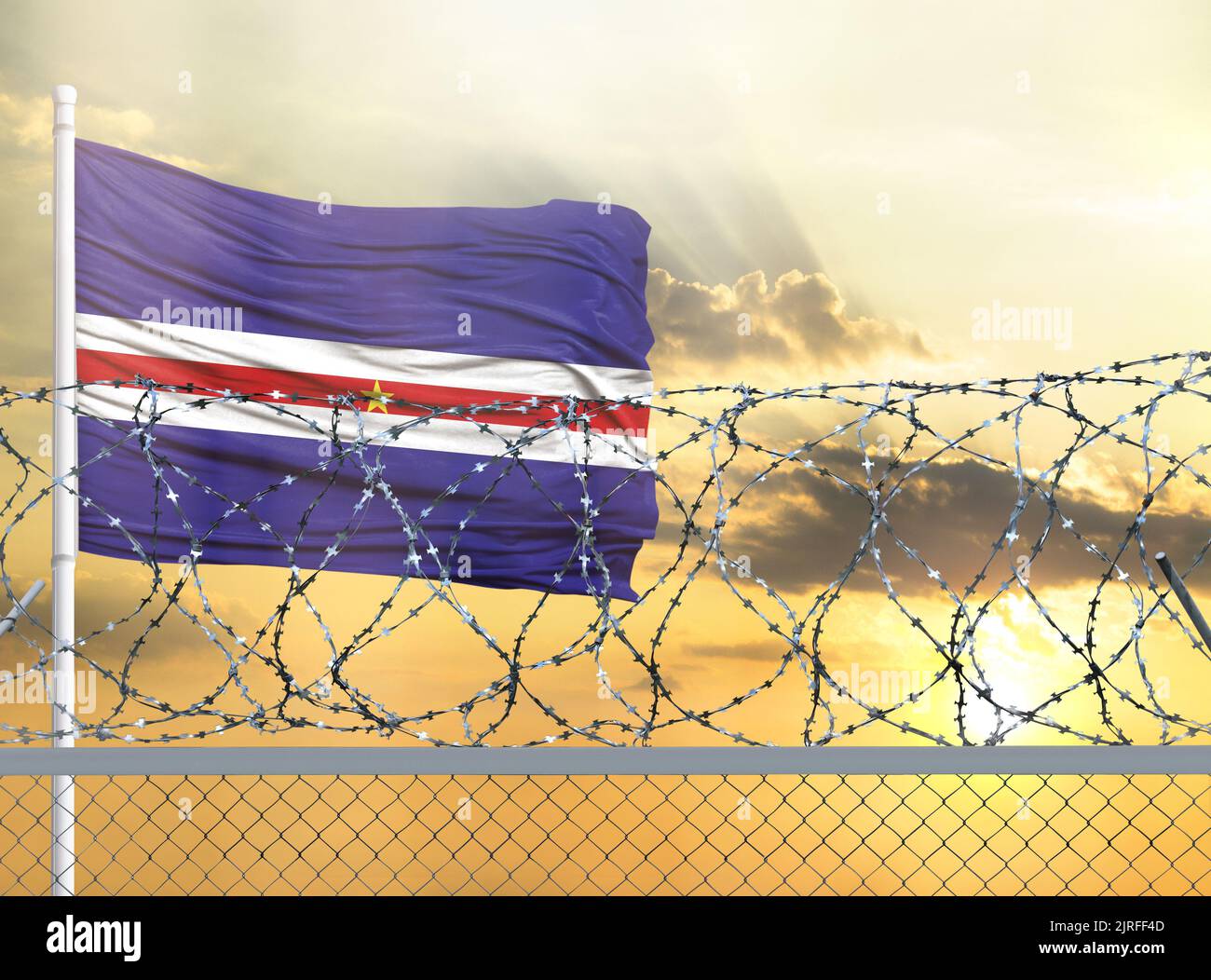 Flagpole with the flag of Cape verde against the sky and behind a fence ...
