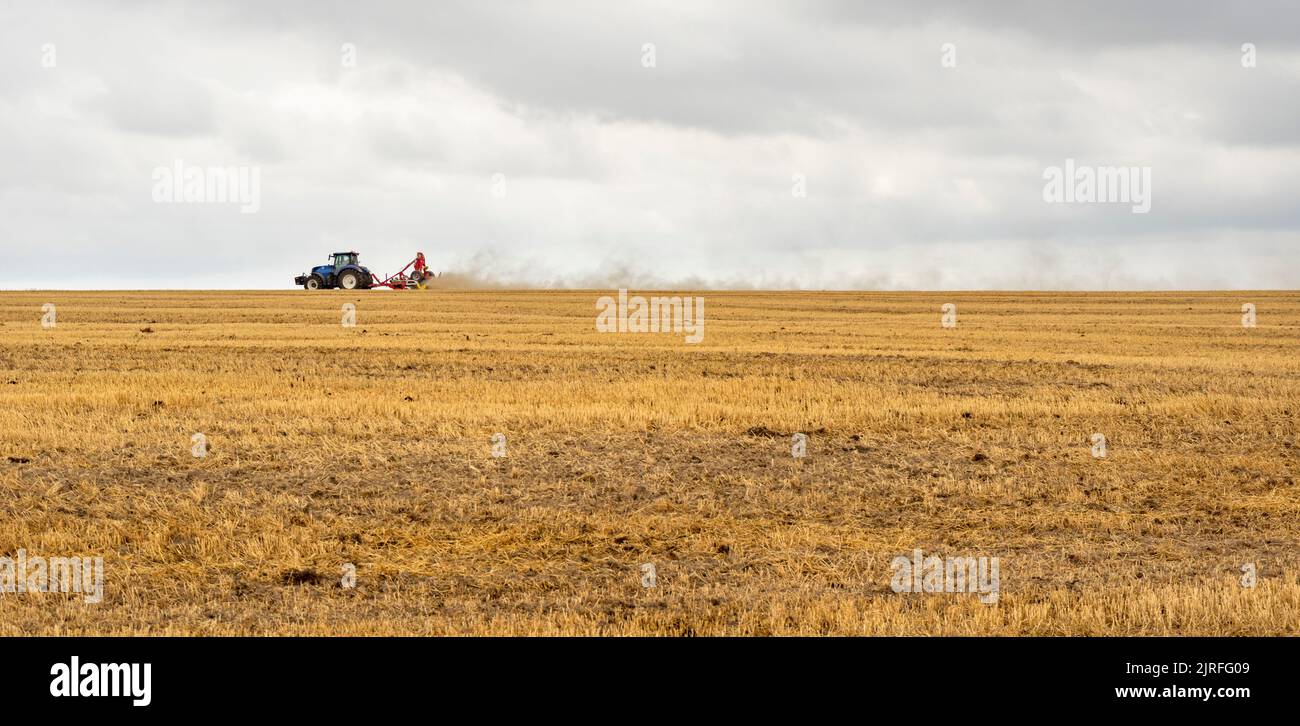 Stormy farmland scenery showing a Tractor on a stubble field in ...