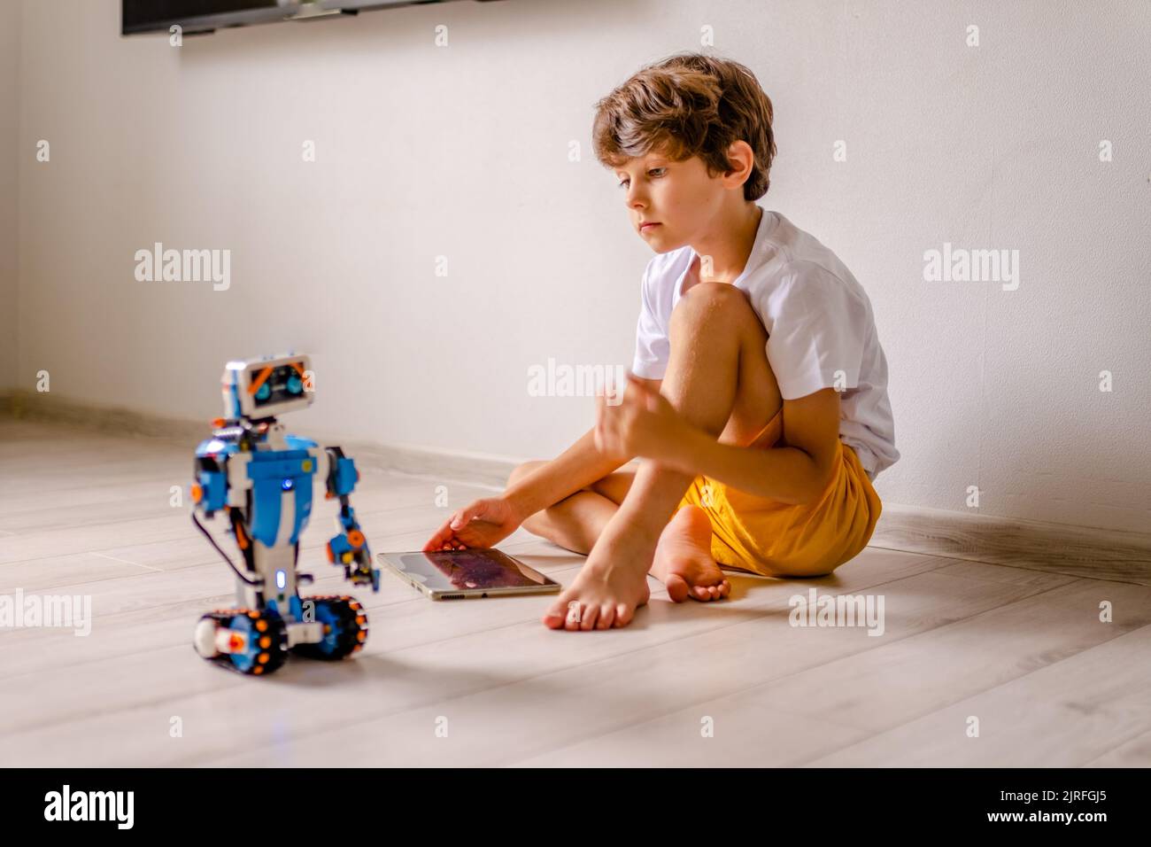 Kid programming robot from plastics details and programmed on tablet ...