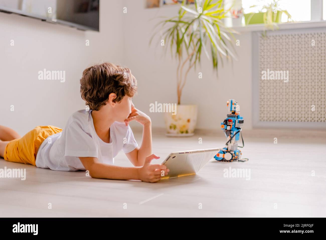 Kid programming robot from plastics details and programmed on tablet ...