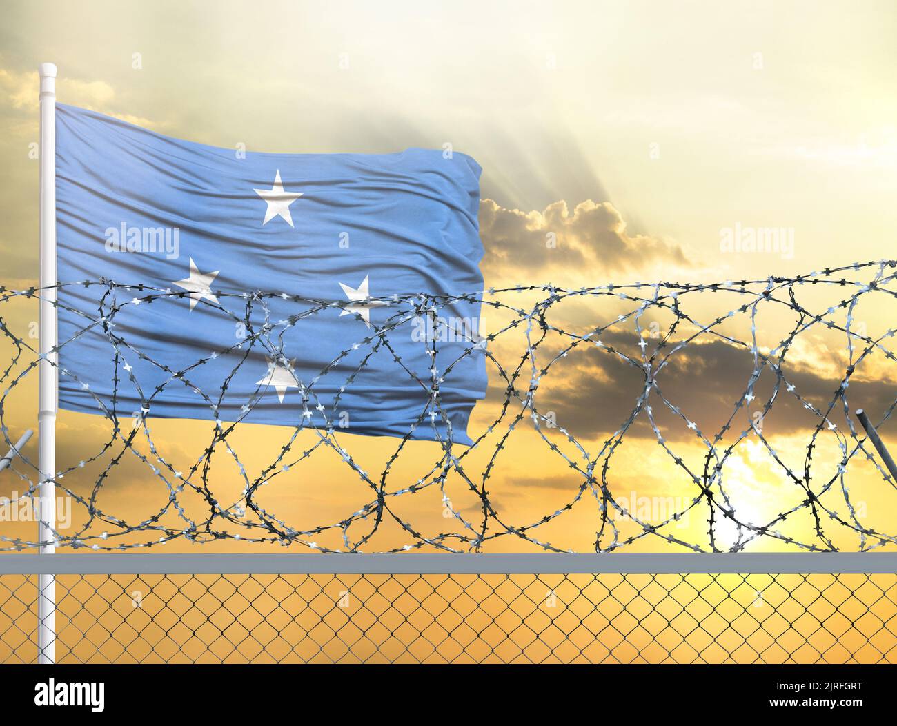 Flagpole with the flag of Micronesia against the sky and behind a fence ...