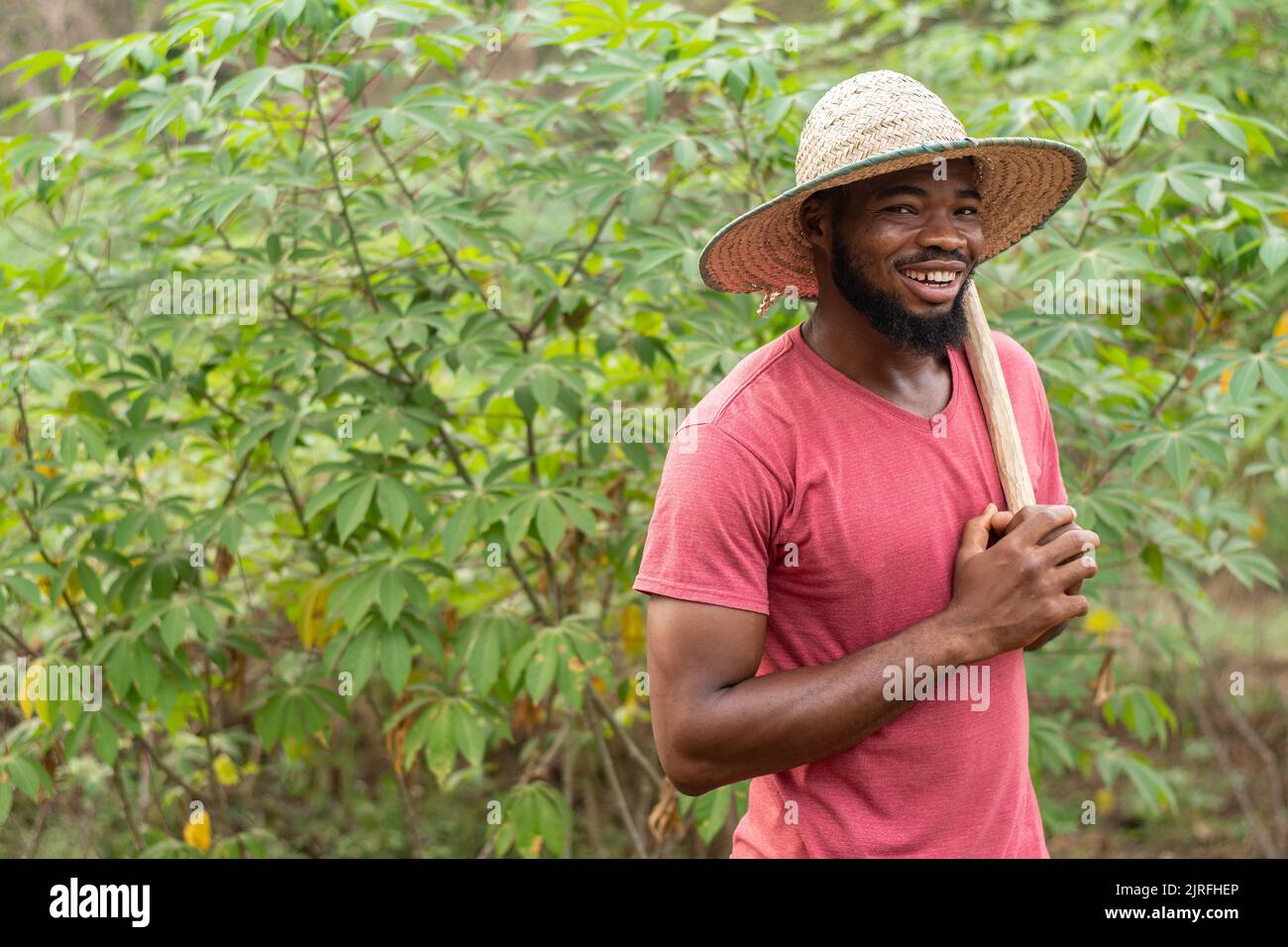 smiling african farmer carrying a hoe Stock Photo - Alamy