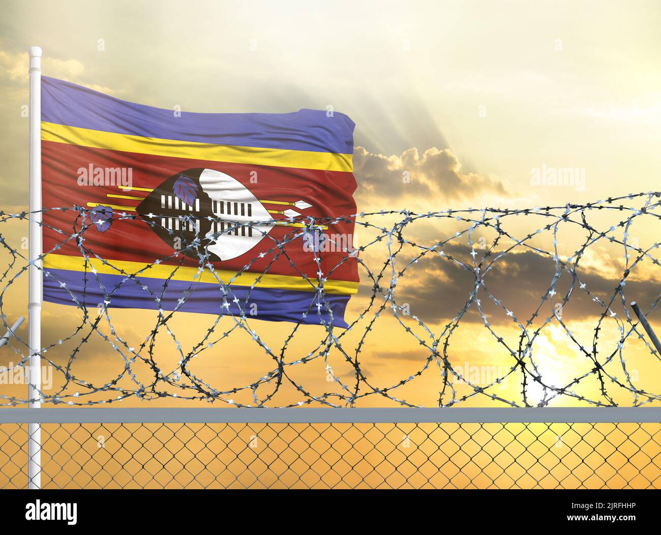 Flagpole with the flag of Swaziland against the sky and behind a fence ...
