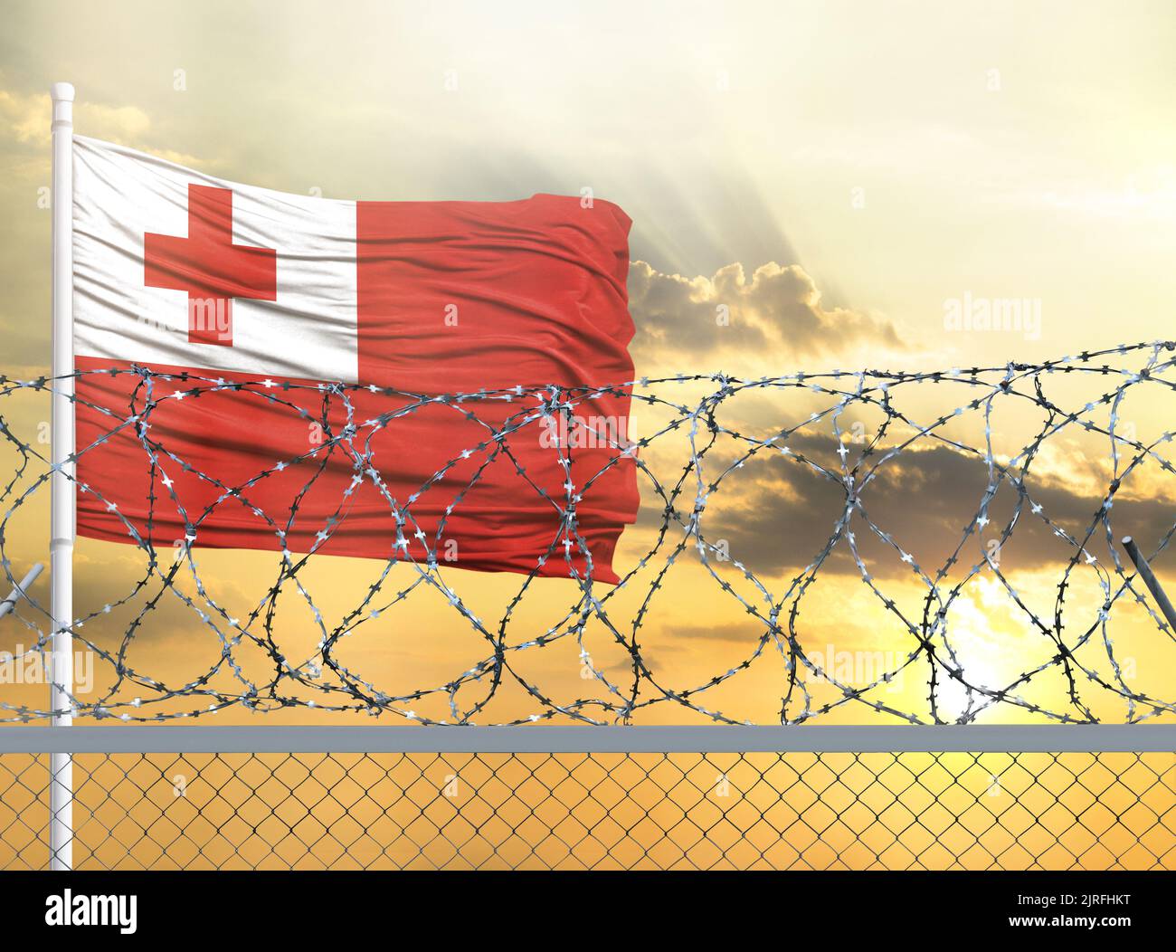 Flagpole with the flag of Tonga against the sky and behind a fence with ...