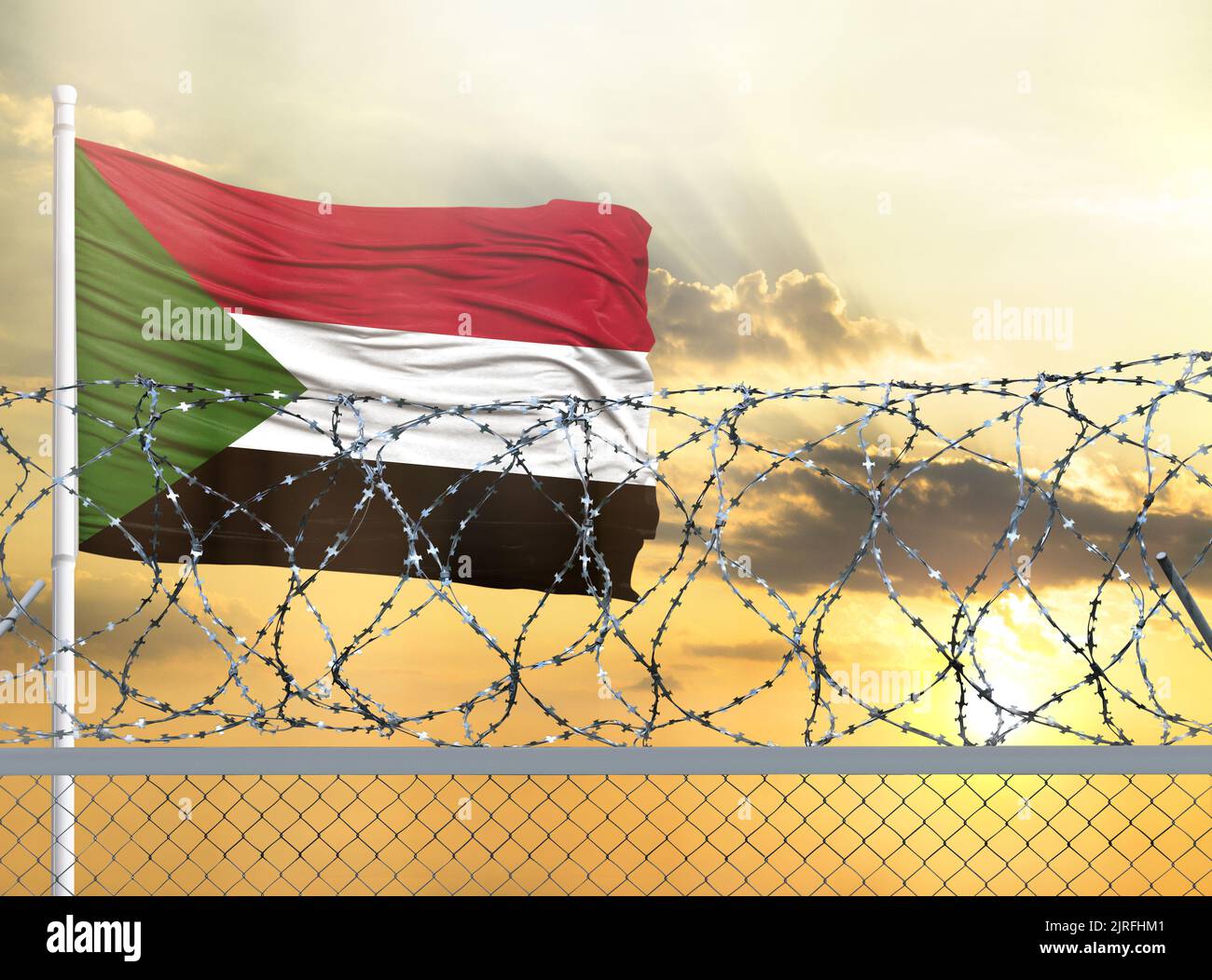 Flagpole with the flag of Sudan against the sky and behind a fence with ...