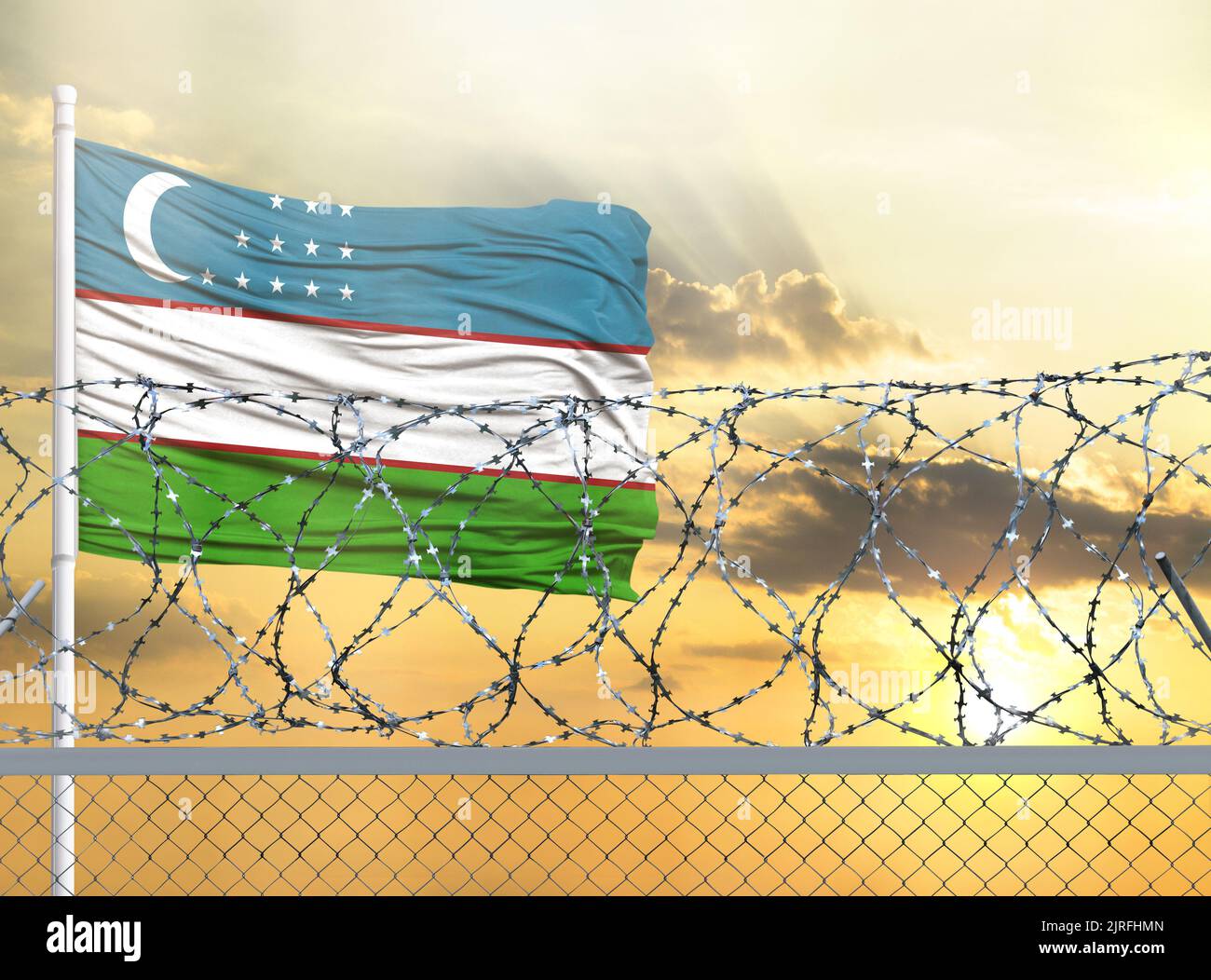 Flagpole with the flag of Uzbekistan against the sky and behind a fence ...