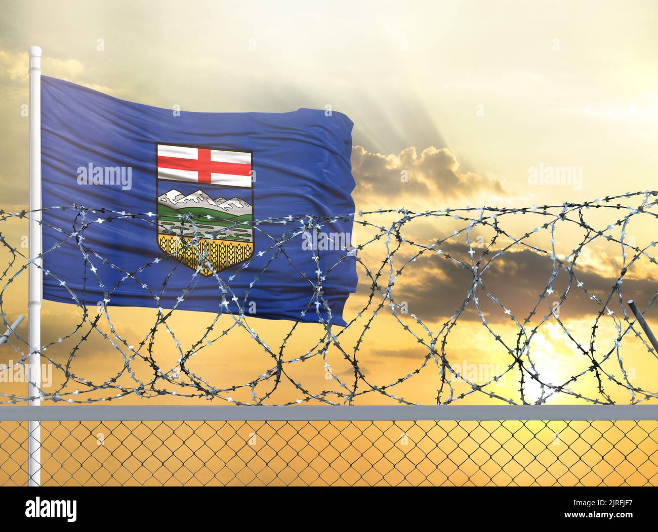 Flagpole with the flag of Alberta against the sky and behind a fence ...