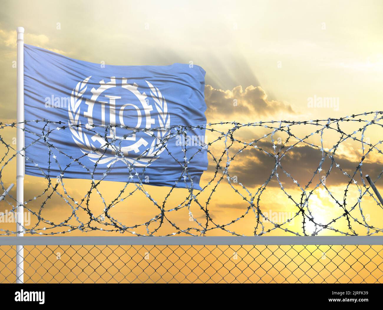 Flagpole with the flag of ILO against the sky and behind a fence with ...