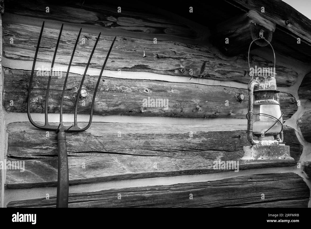 Old pitch fork and lantern on the side of a log building Stock Photo ...