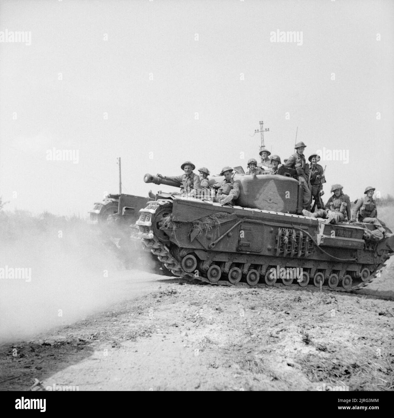 A Churchill tank carrying infantry advances towards St Pierre ...