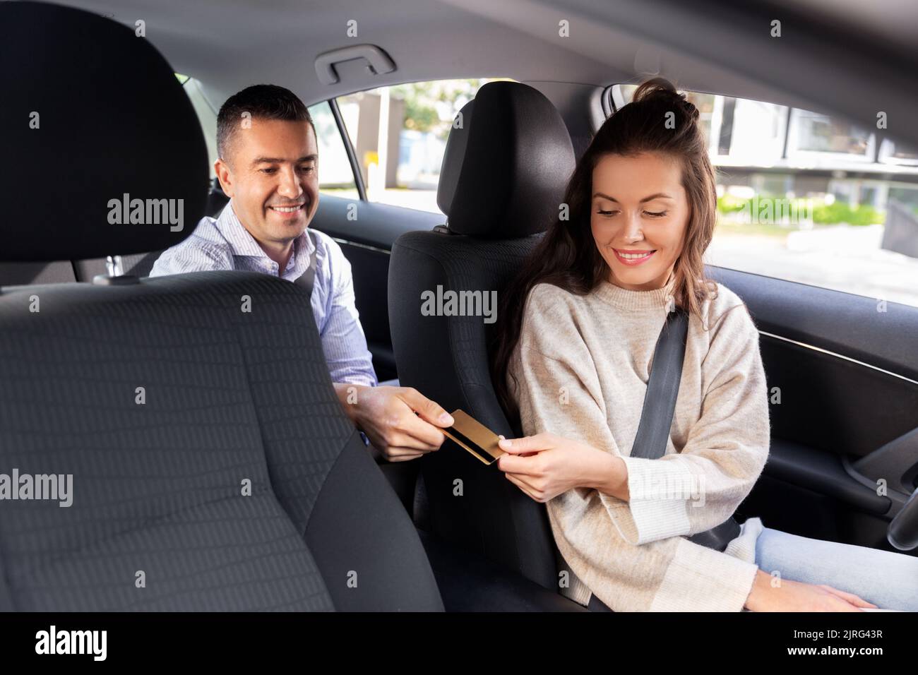 female car driver takes credit card from passenger Stock Photo - Alamy