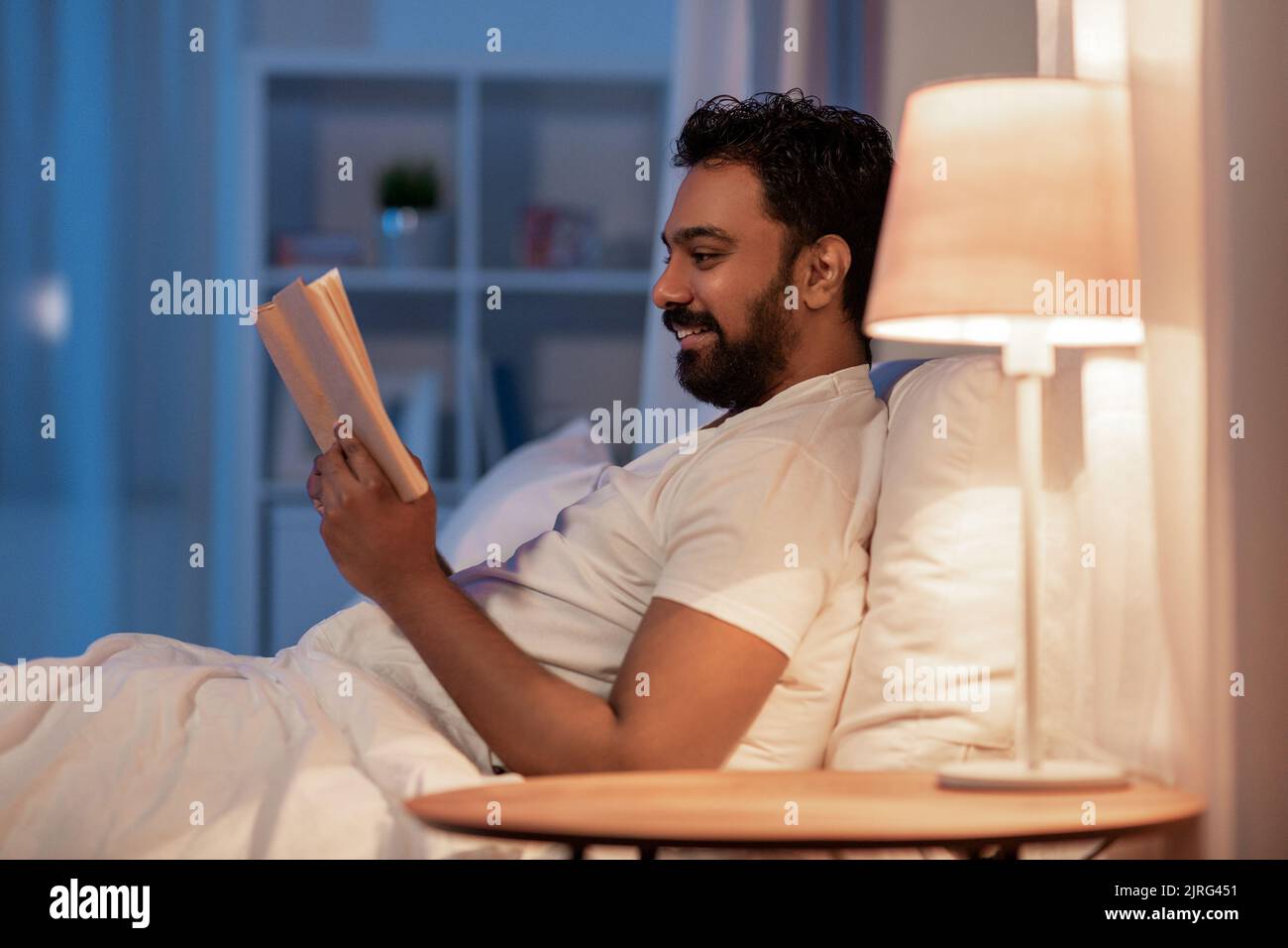 happy indian man reading book in bed at night Stock Photo - Alamy