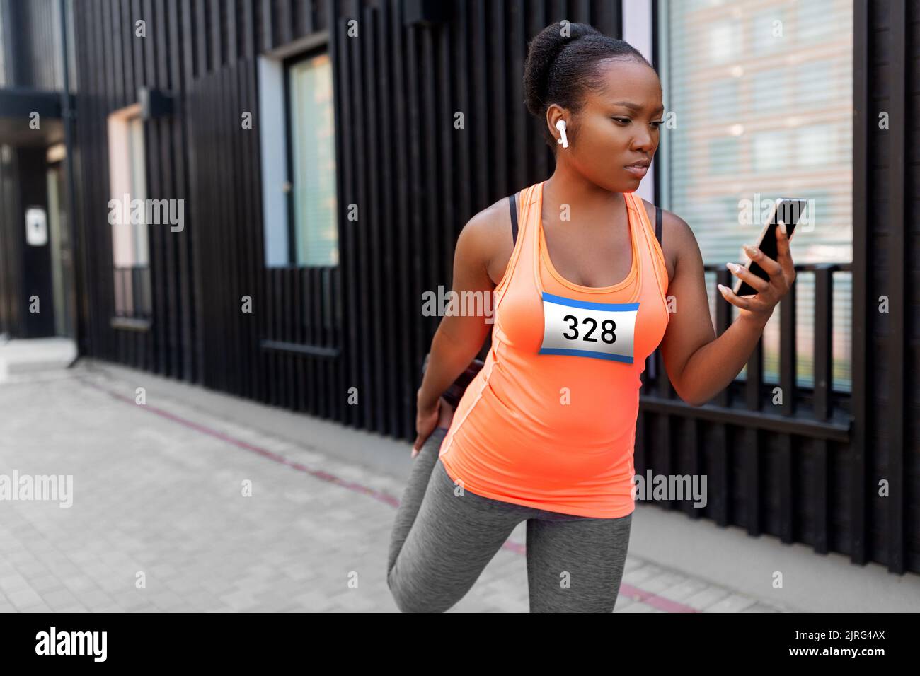 female marathon runner with smartphone stretching Stock Photo - Alamy