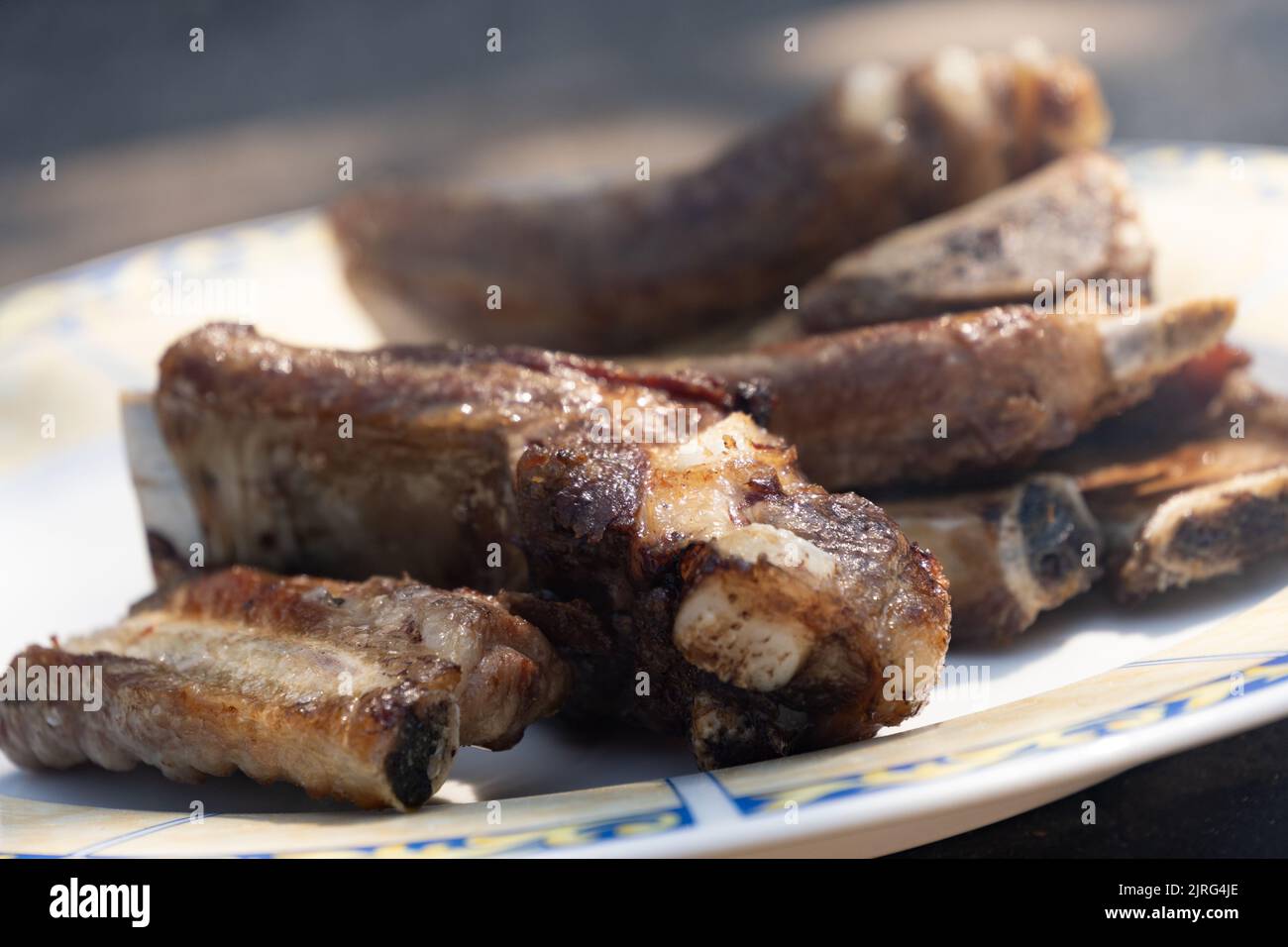 Close-up with defocused background of pork ribs cooked on a wood-fired ...