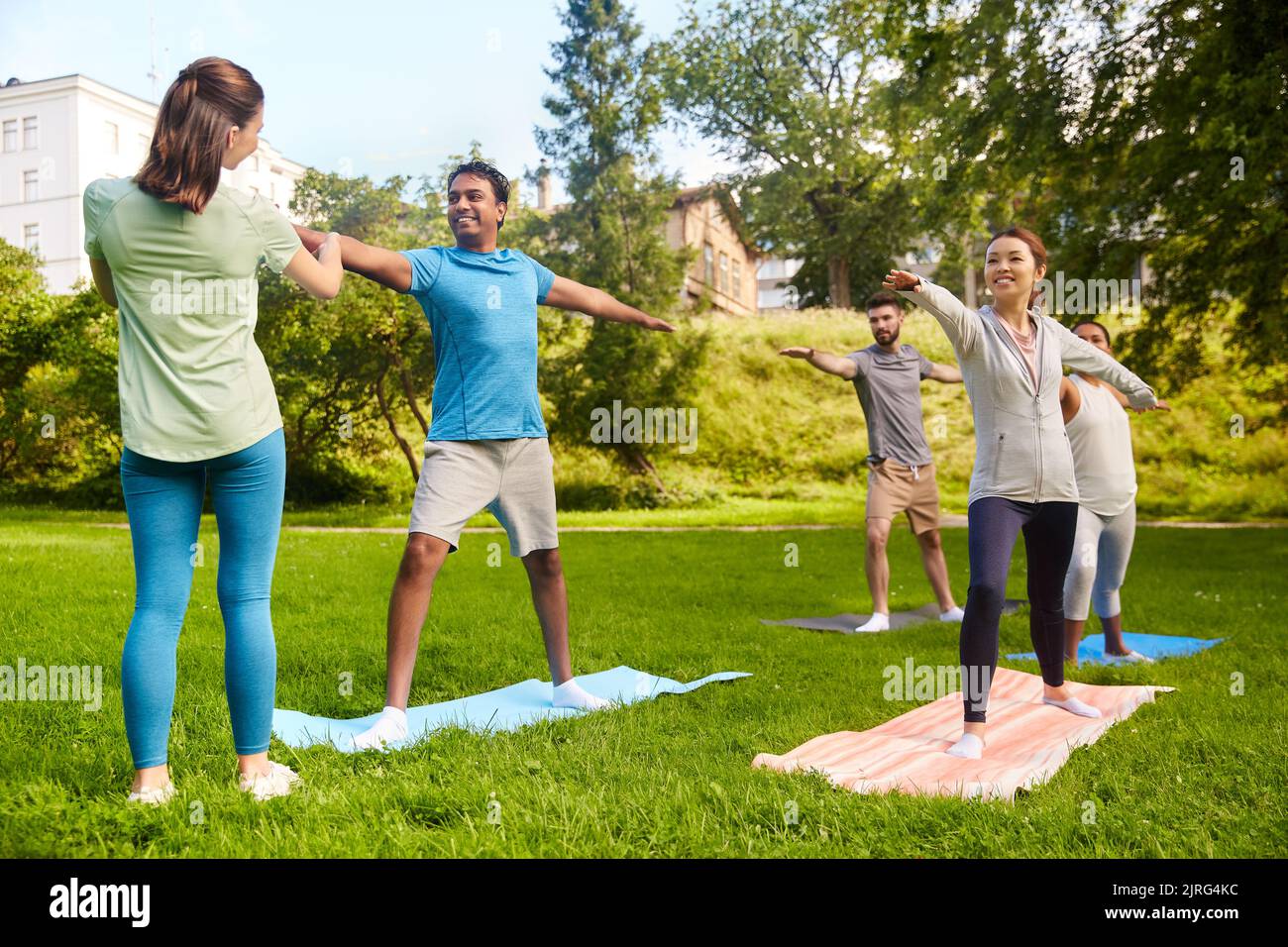 group of people doing yoga with instructor at park Stock Photo - Alamy