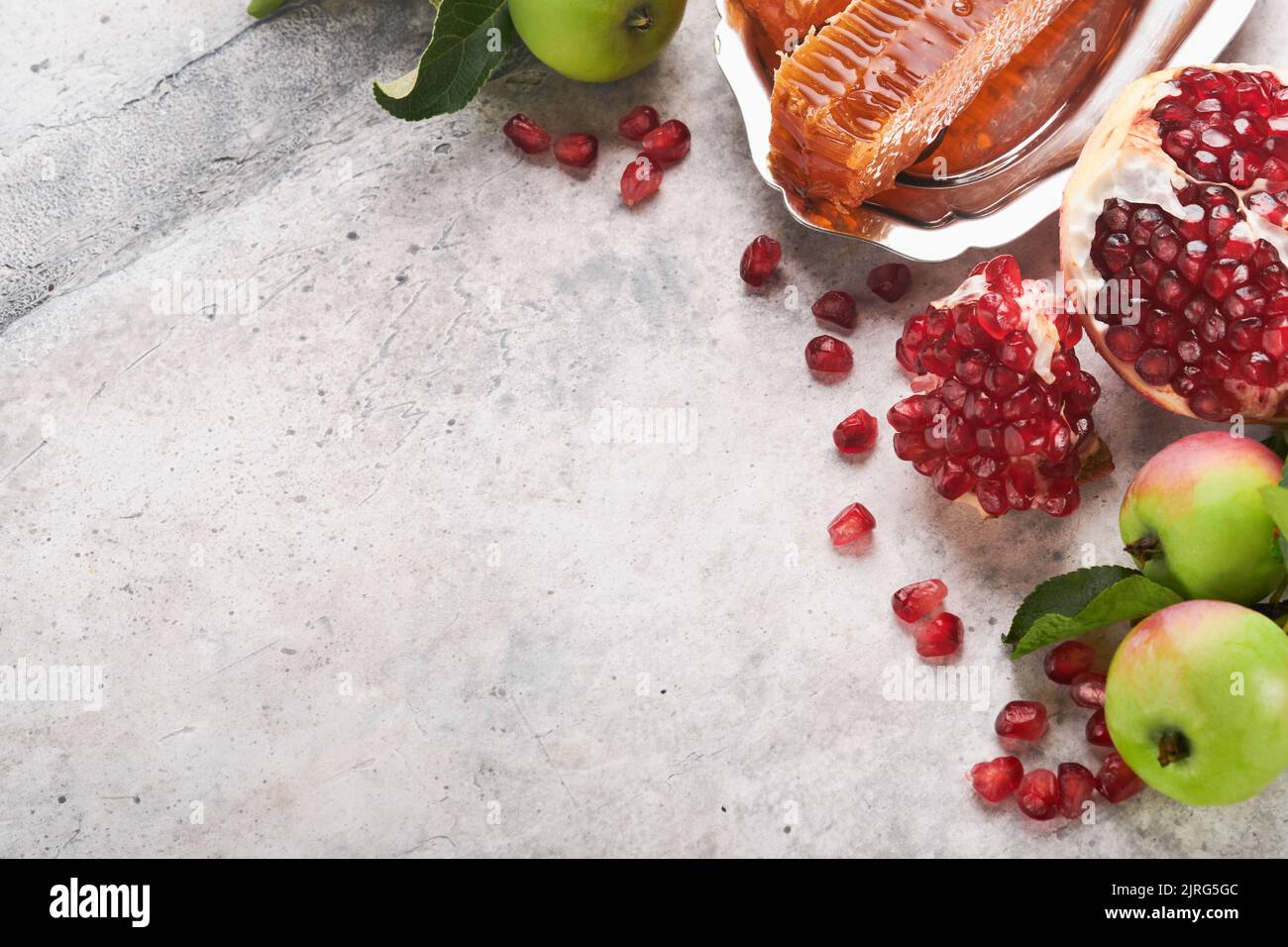 Rosh Hashanah. Honey jar, honeycomb, apple and pomegranate on gray old ...