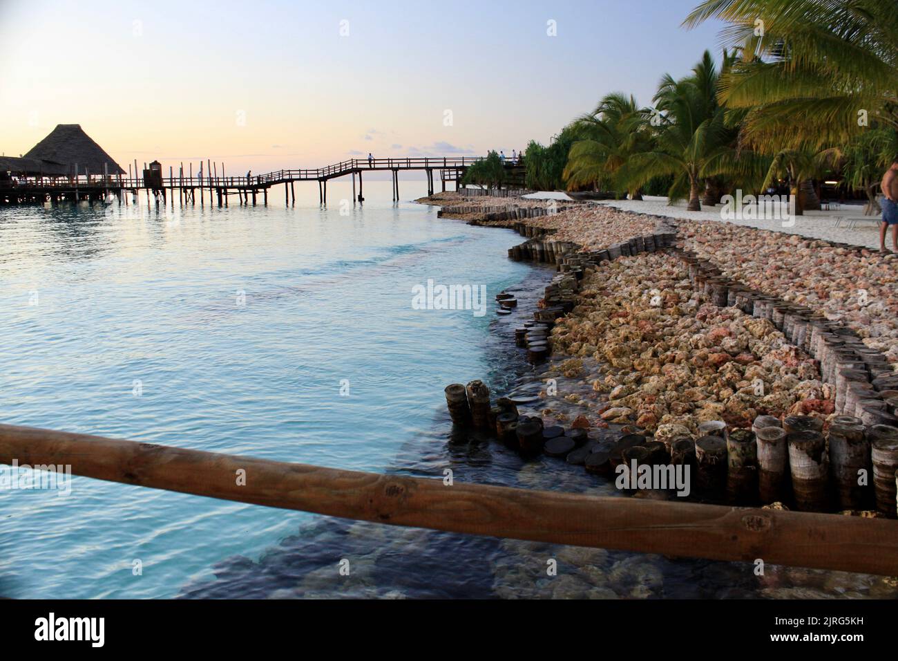 The view of a wooden bridge crossing over the blue water connecting the ...