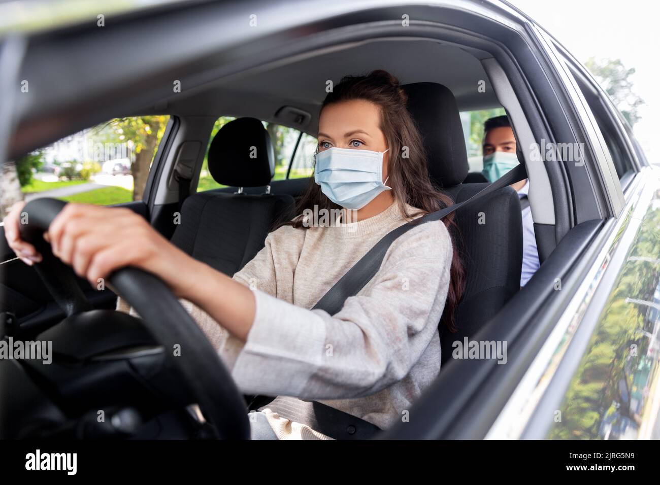 female driver in mask driving car with passenger Stock Photo - Alamy