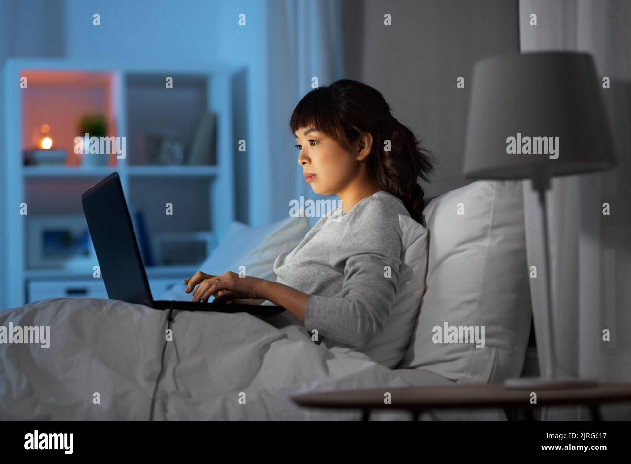 woman with laptop in bed at home at night Stock Photo - Alamy