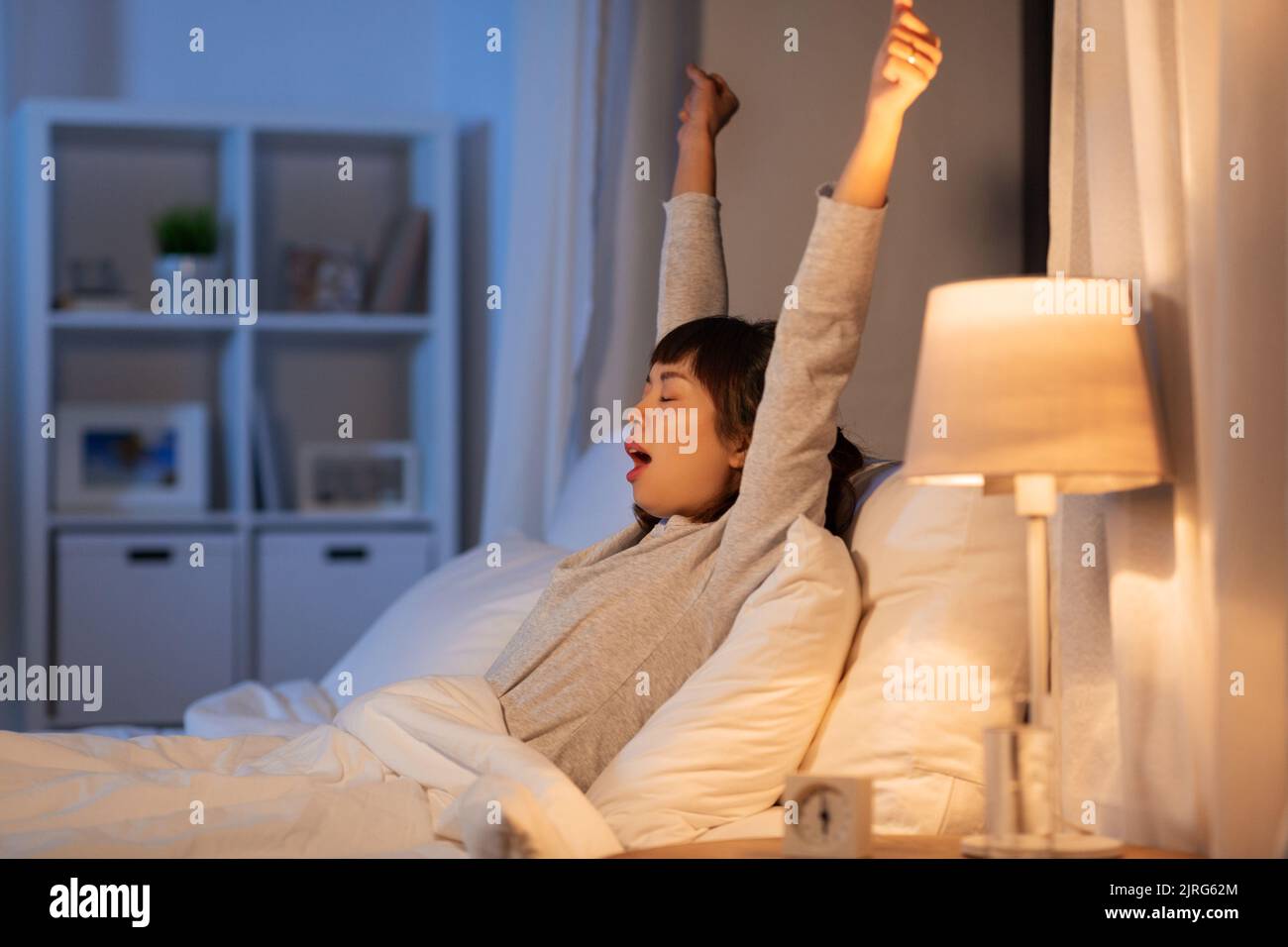 tired asian woman stretching in bed at night Stock Photo - Alamy