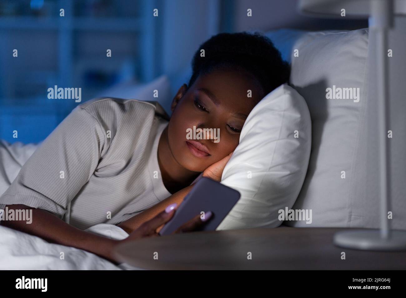 african woman with smartphone in bed at night Stock Photo - Alamy
