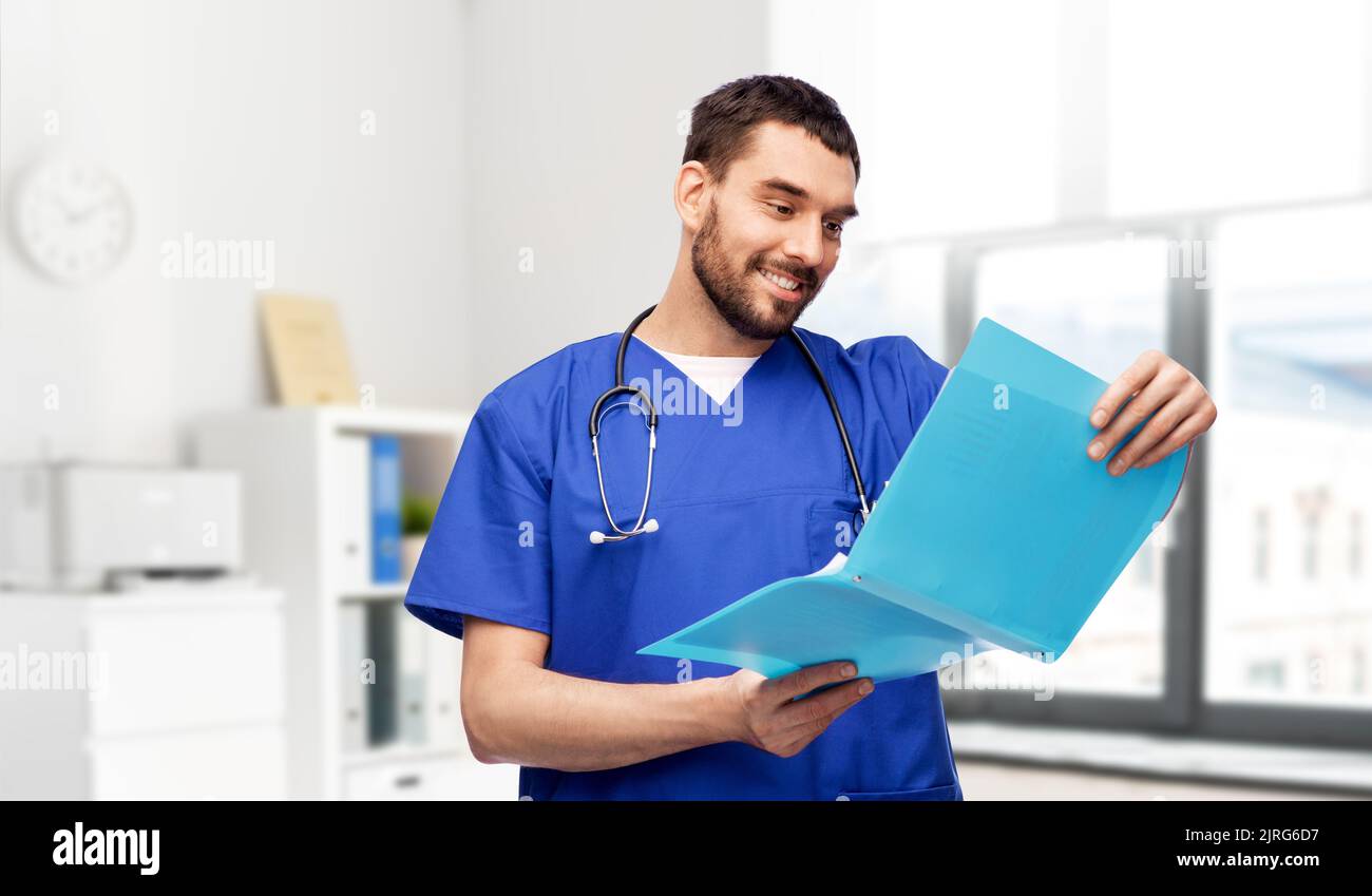 happy male doctor reading medical report in folder Stock Photo - Alamy