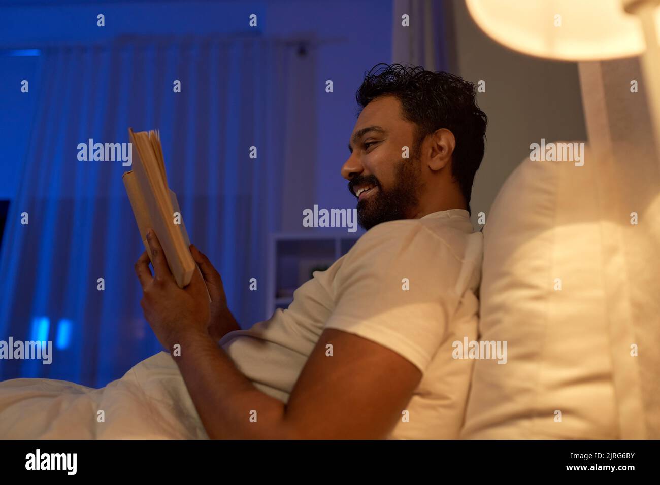happy indian man reading book in bed at night Stock Photo - Alamy