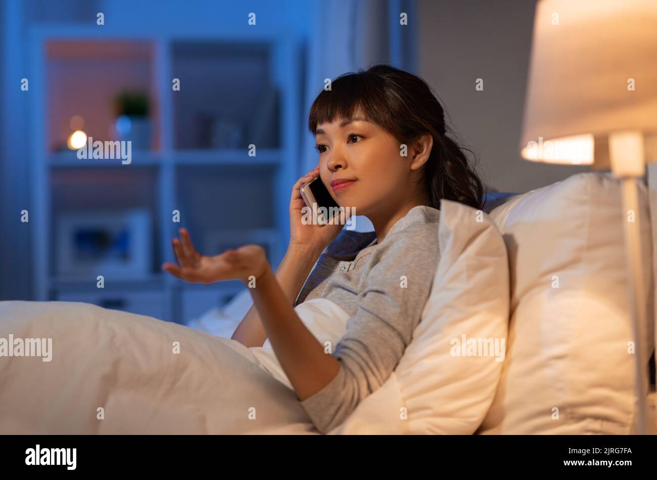 asian woman calling on smartphone in bed at night Stock Photo - Alamy