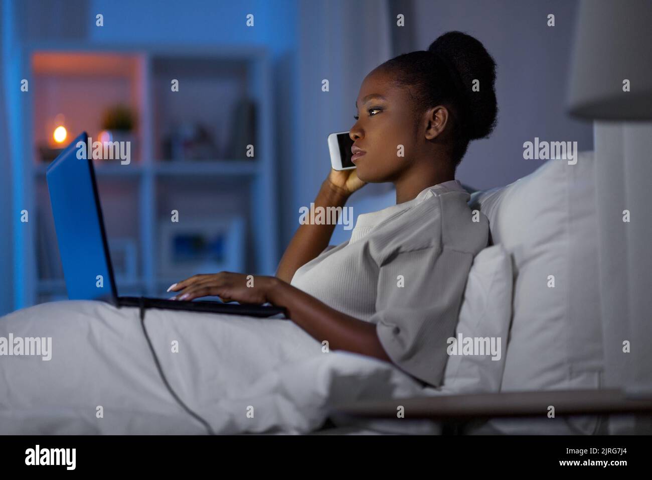 woman with laptop calling on smartphone in bed Stock Photo - Alamy