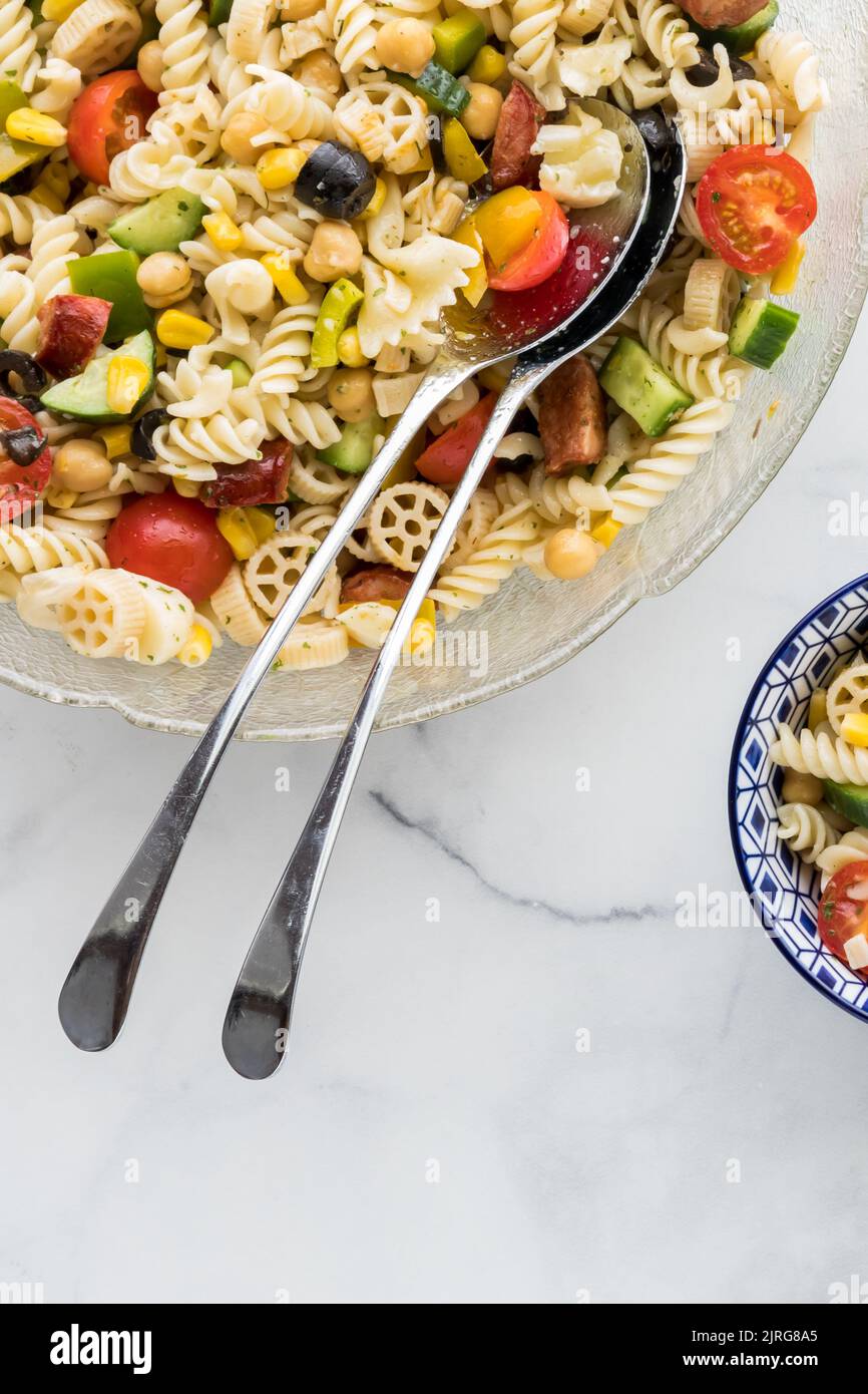 Above view of a pasta salad with long metal salad servers. Copy space ...