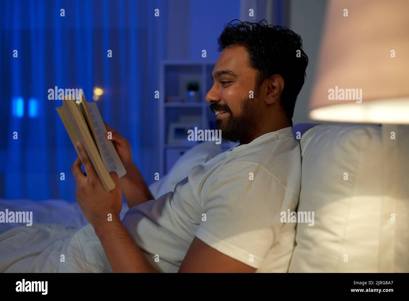 happy indian man reading book in bed at night Stock Photo - Alamy