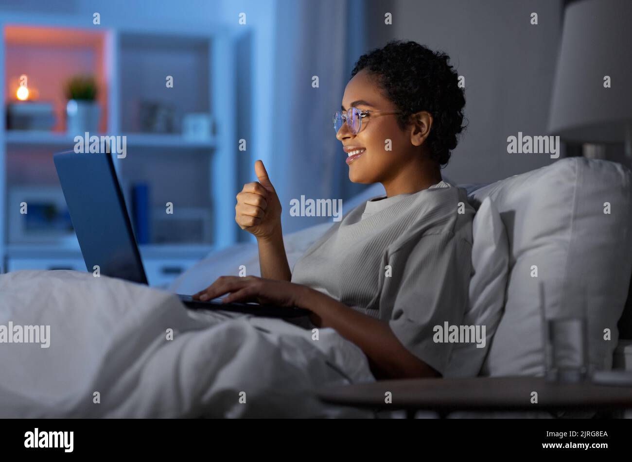 woman having video call on laptop in bed at night Stock Photo - Alamy