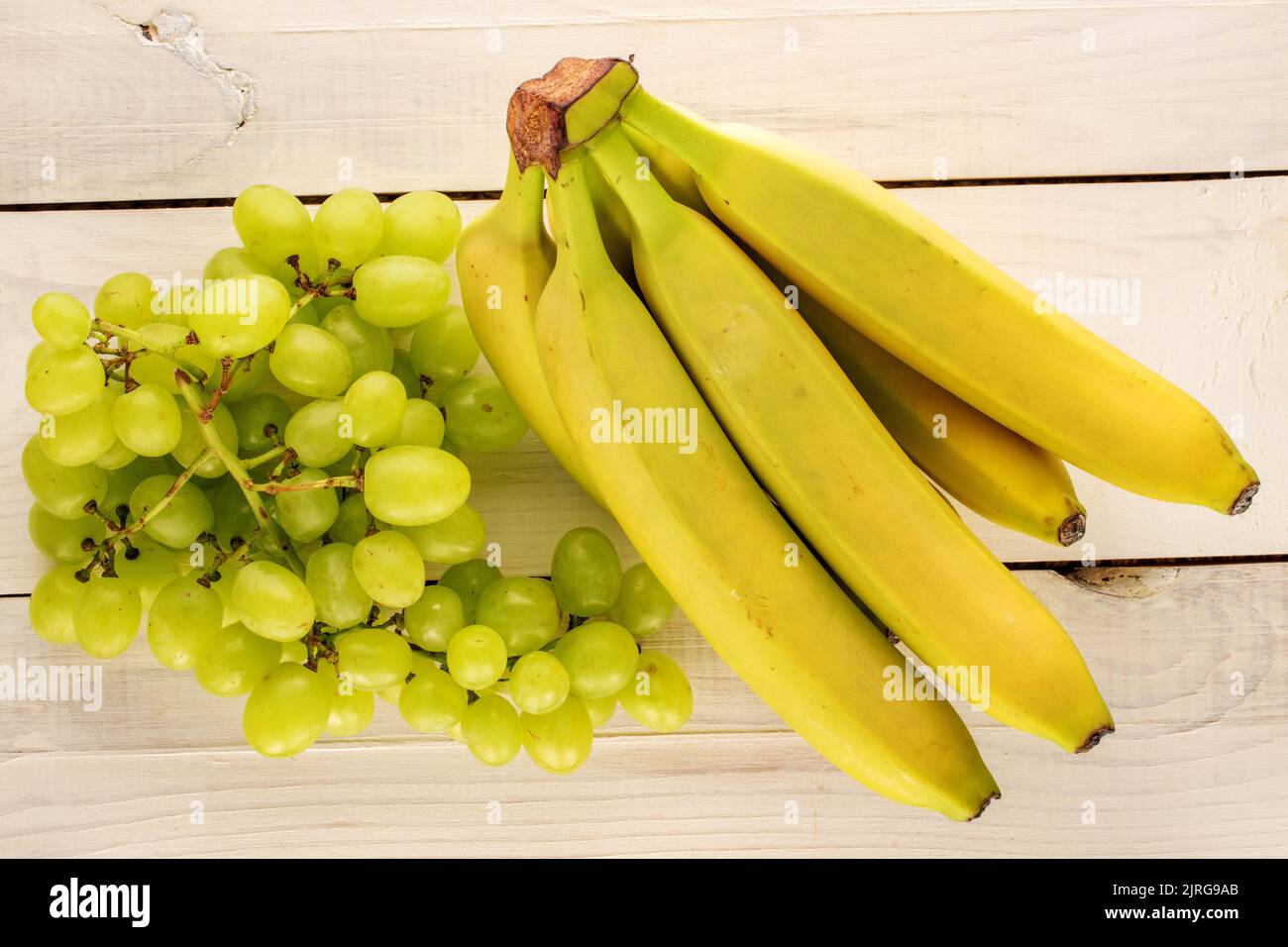 One bunch of white grapes and bananas on a wooden table, close-up, top ...