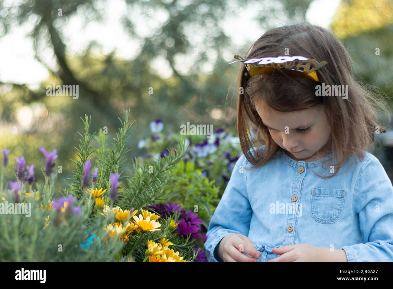A small beautiful modest girl with a crown happy birthday on her head ...