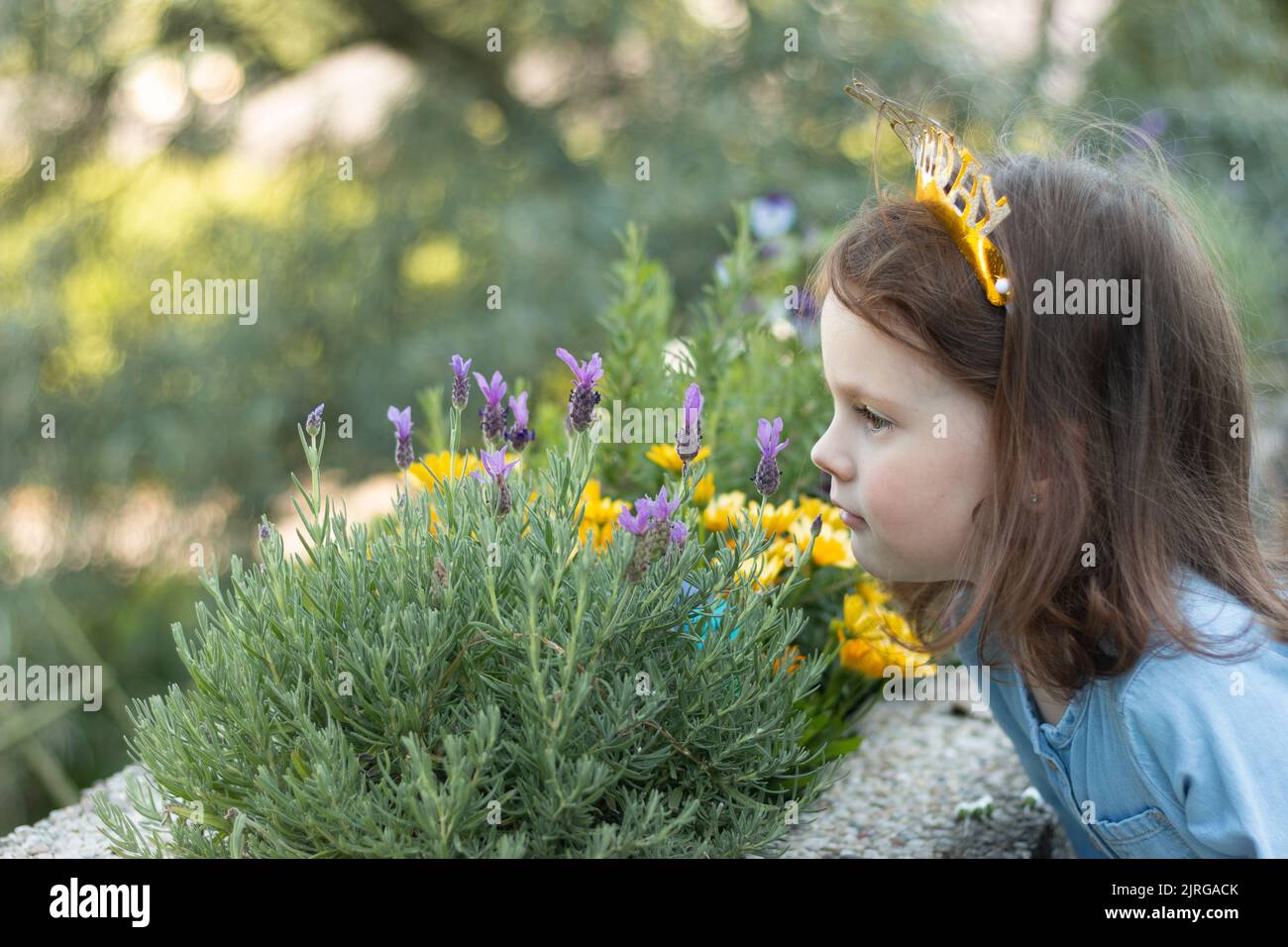 A small beautiful modest girl with a crown happy birthday on her head ...