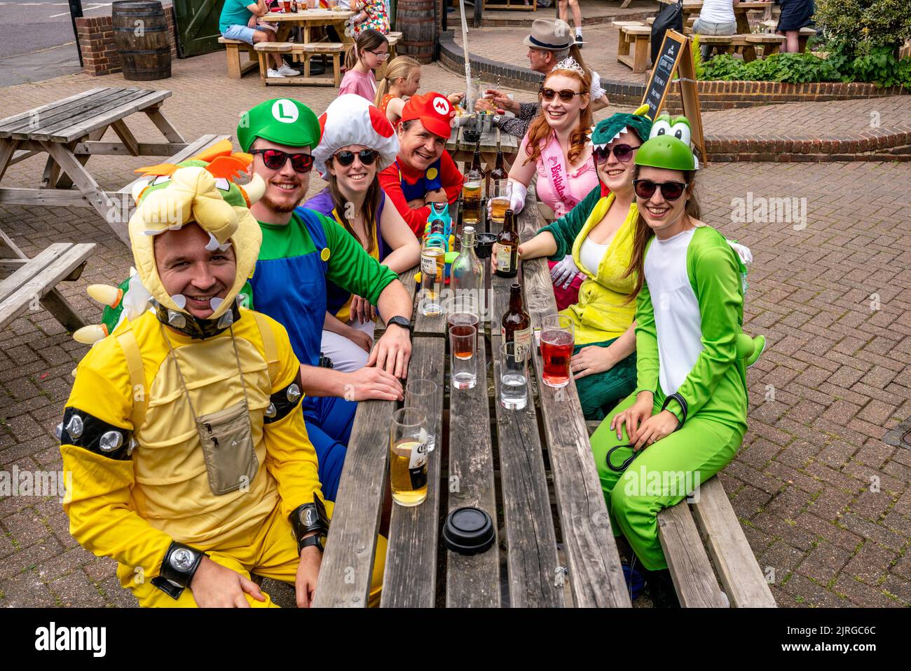 A Group Of Young People In Fancy Dress Costumes Sitting Down Drinking ...