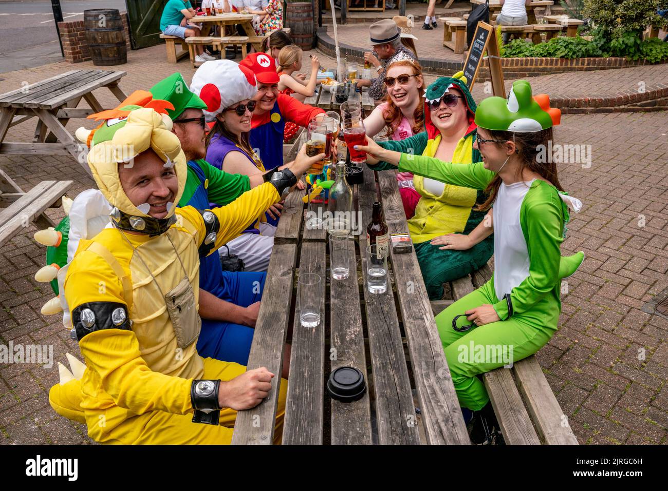 A Group Of Young People In Fancy Dress Costumes Sitting Down Drinking ...