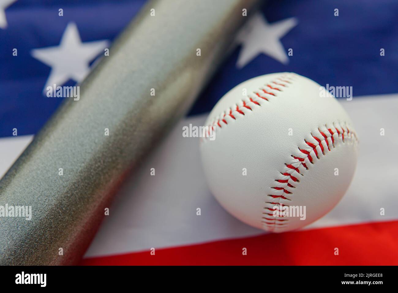 White leather ball and baseball bat laying on flag of the United States ...