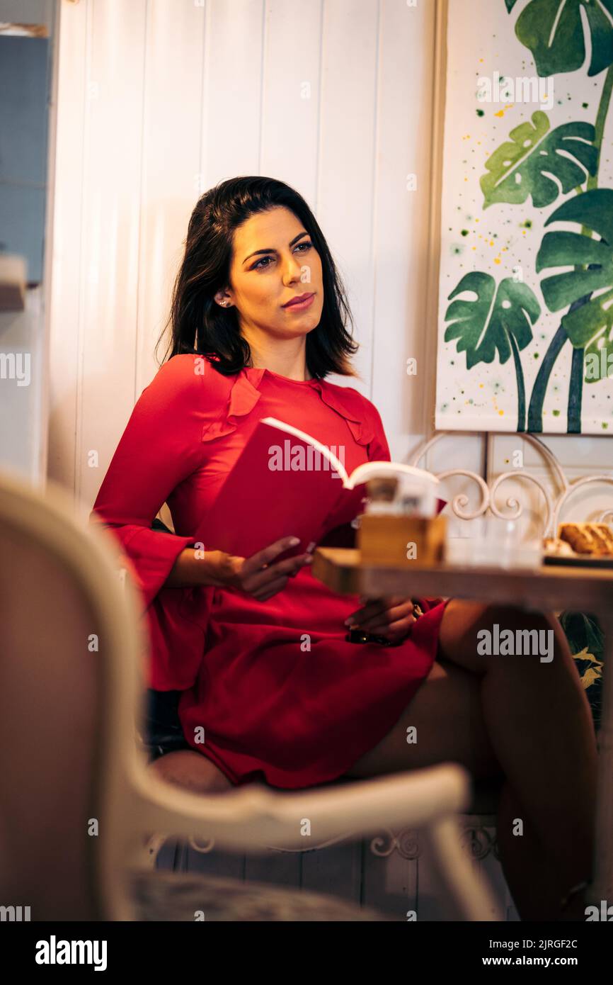 An interesting and attractive woman looks into infinity with a book in ...