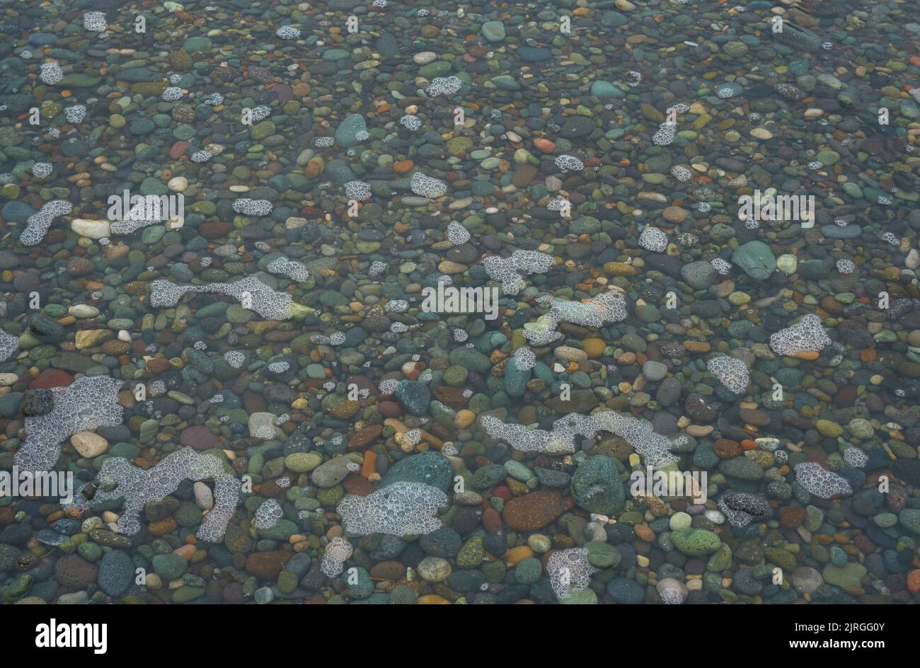 Pebble beach flooded with water after high tide Stock Photo - Alamy
