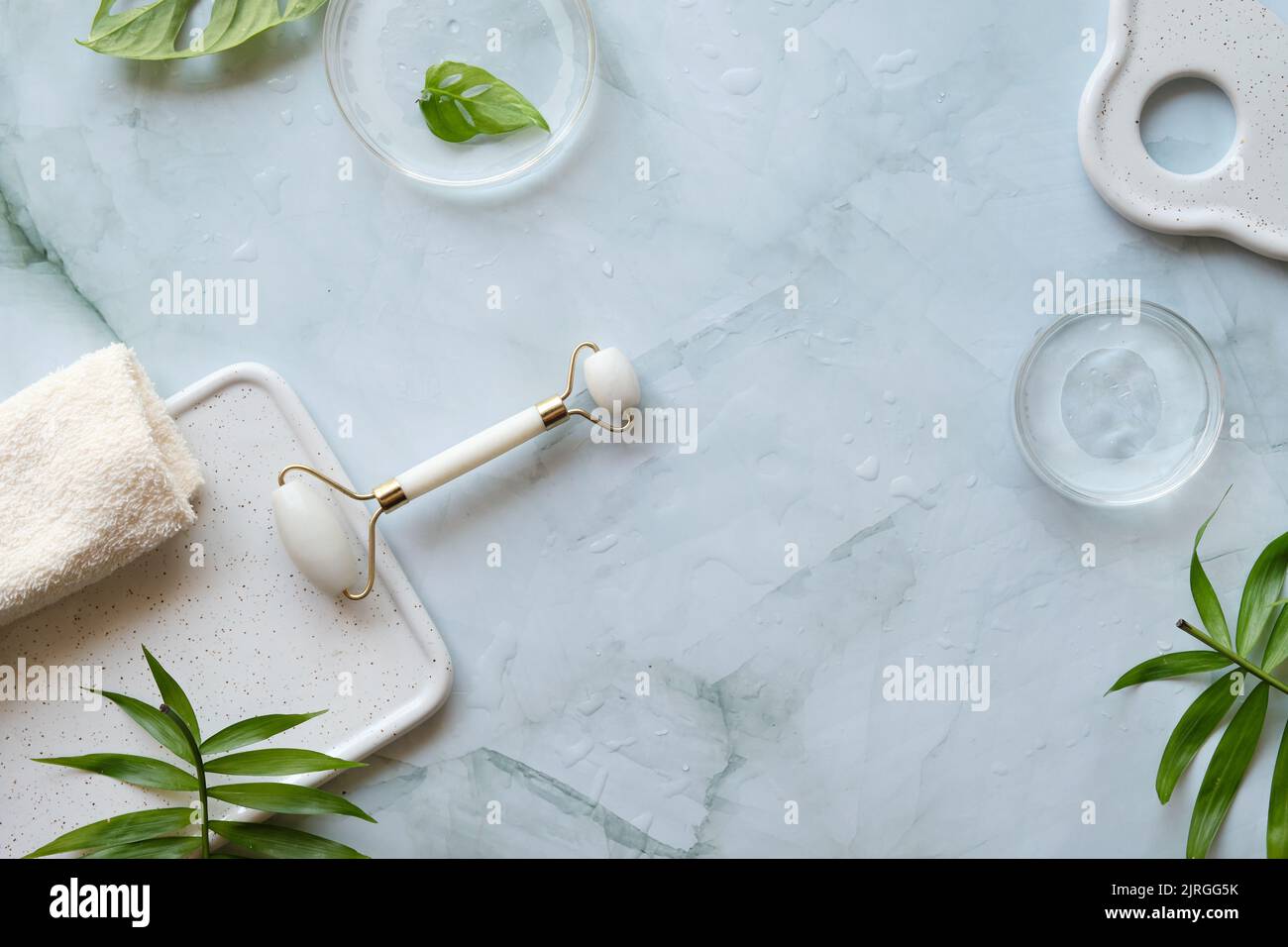 Home made moisturizer and green jade stone face roller on off white ...