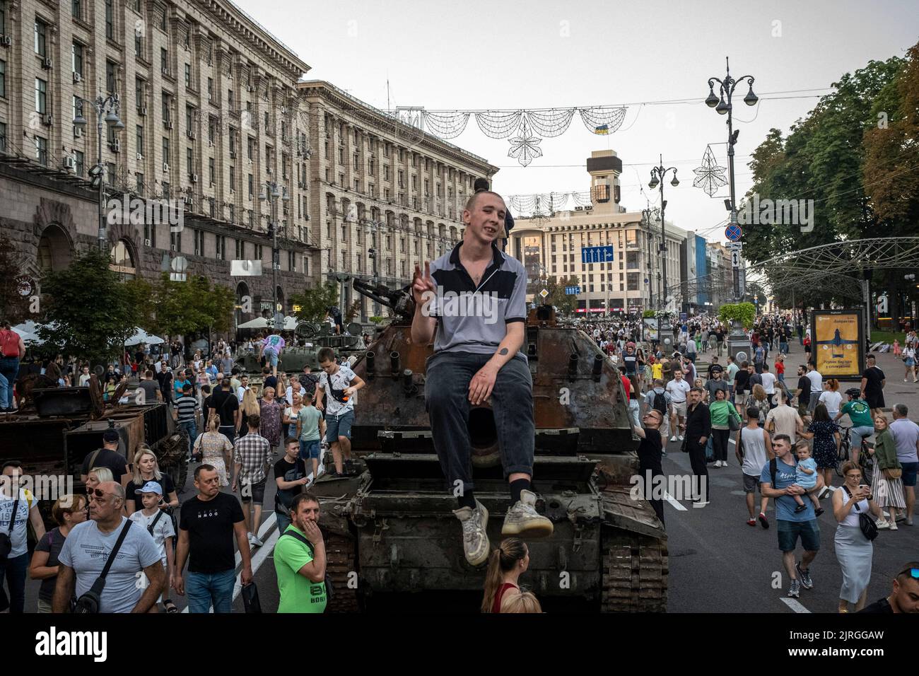 A man sits on the turret of the wreckage of a Russian military vehicle ...