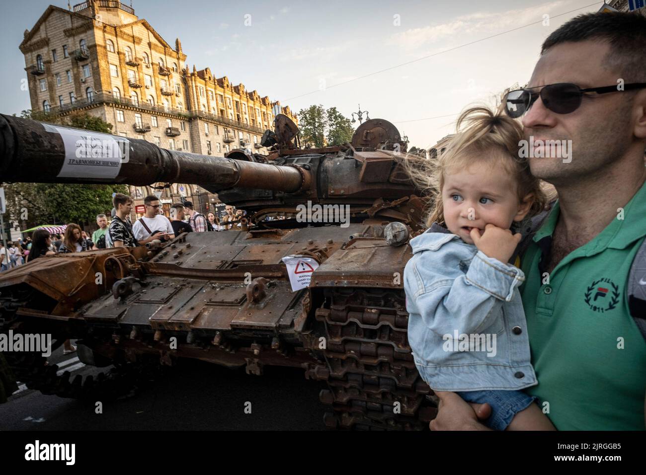 Father holding his daughter walk past the wreckage of a Russian tank on ...