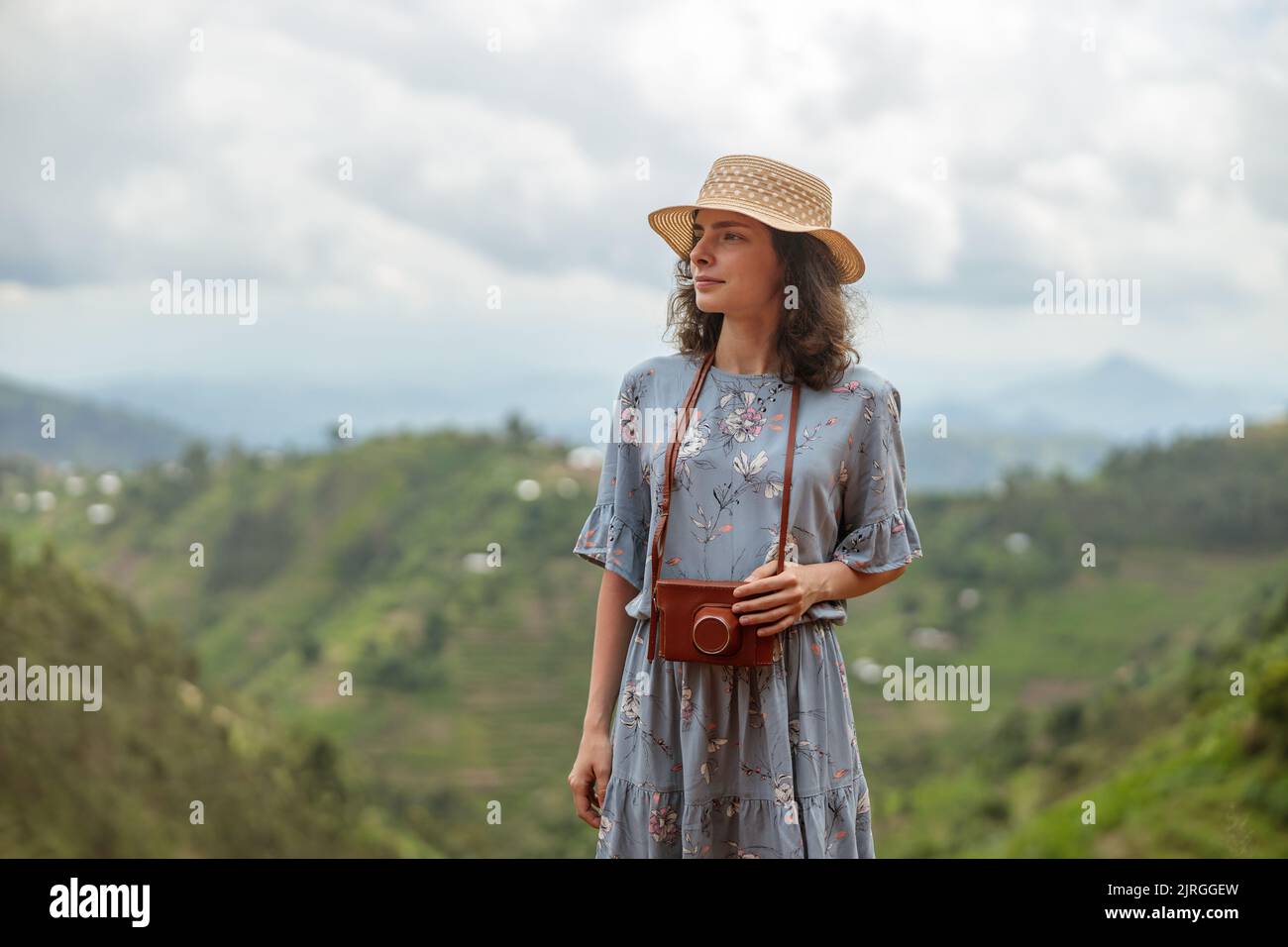 Smiling female traveler with photo camera against of mountains in ...