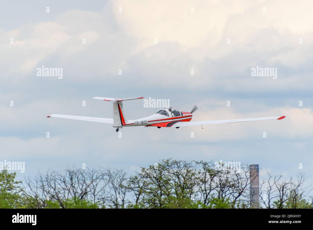 An airplane flying over trees in the show at Hangariada aeronautical ...
