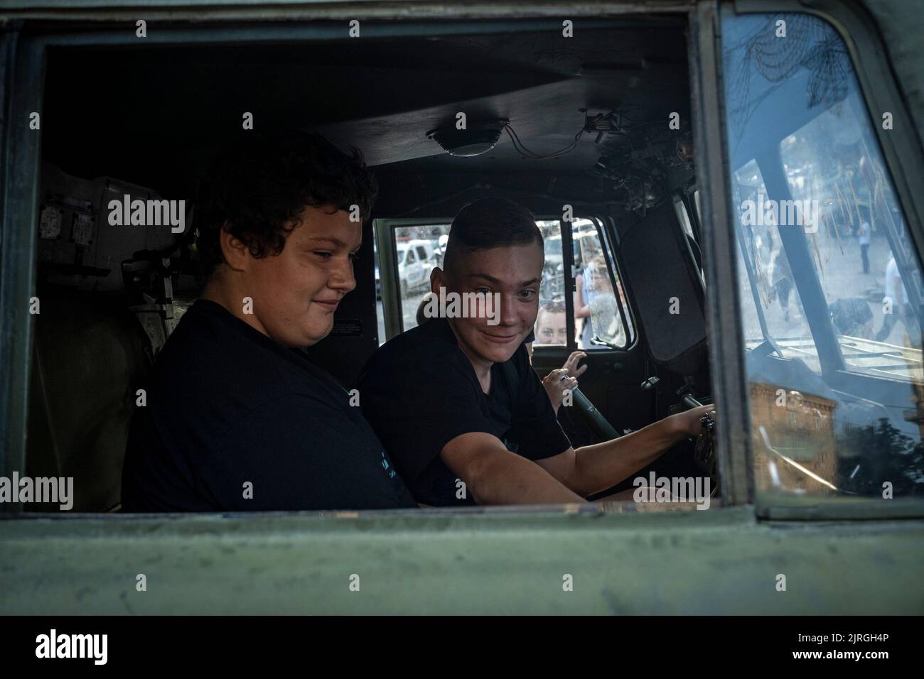Teenagers sit inside the display of destroyed Russian military truck on ...