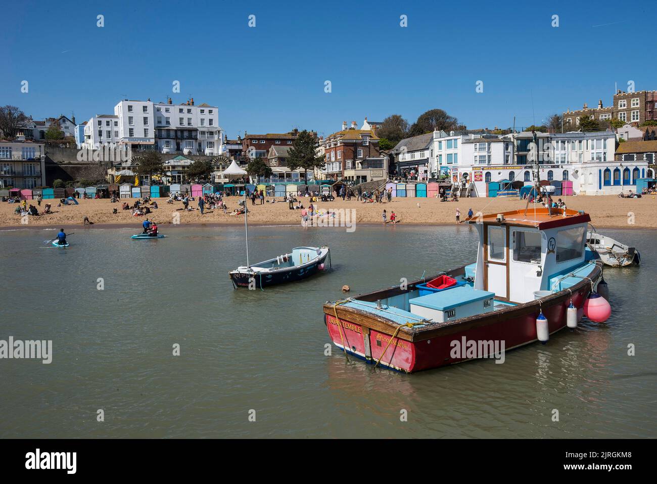 Fishing boats float in the sea while people enjoy the good weather at ...