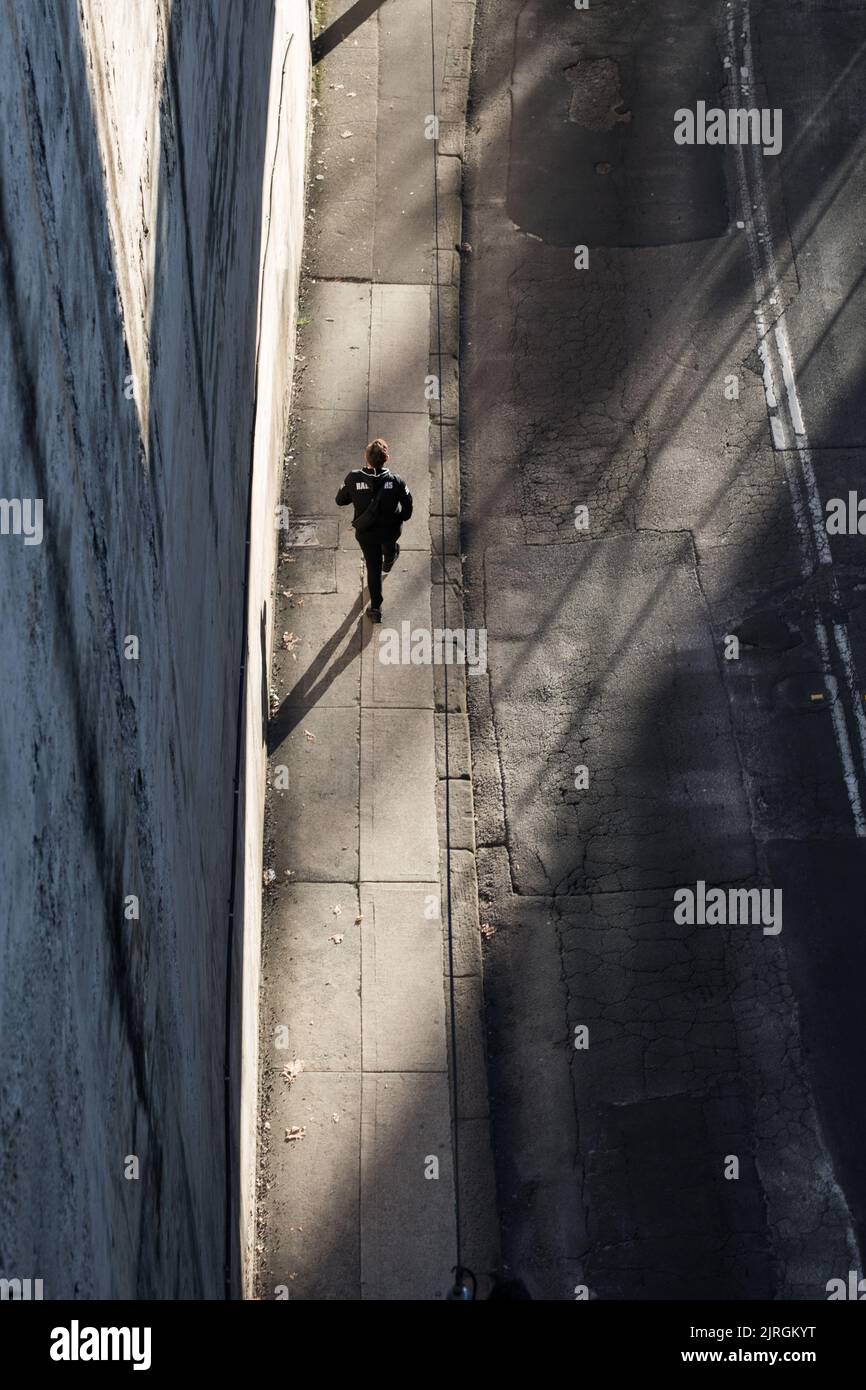 An artsy top view shot of a person walking down a sidewalk under the ...